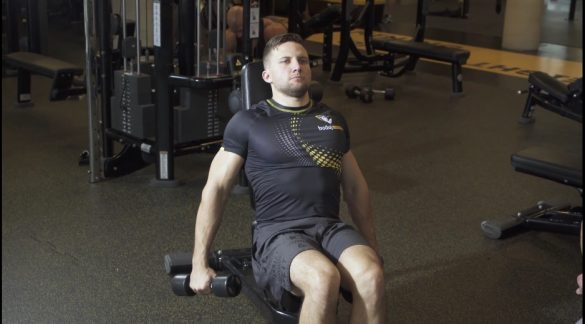 Unoszenie ramion z hantlami w przód siedząc (naprzemienne) - BudujMase.pl