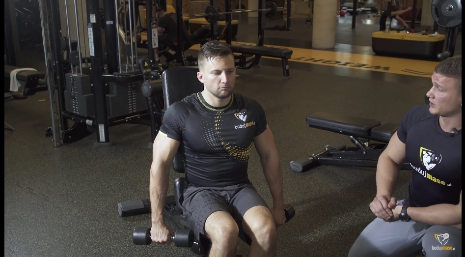 Unoszenie ramion z hantlami na boki siedząc - BudujMase.pl