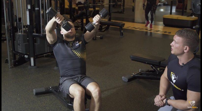 Unoszenie ramion z hantlami do przodu siedząc - BudujMase.pl